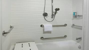 Uma casa de banho moderna com cabine de duche, barras de apoio e banheira.