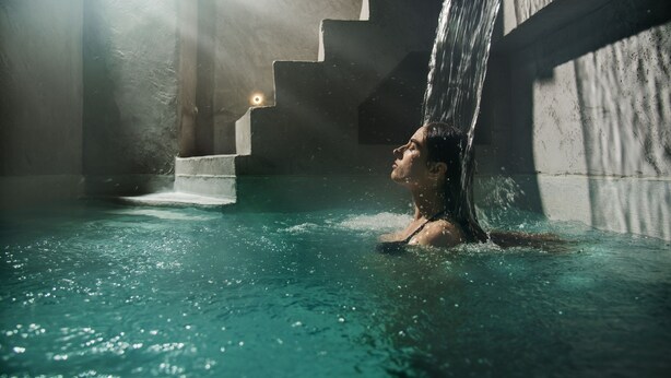 Uma pessoa em uma banheira de spa com cascata.