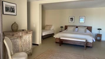Quarto com uma cama grande, uma cama menor, uma cômoda de madeira e uma cadeira.