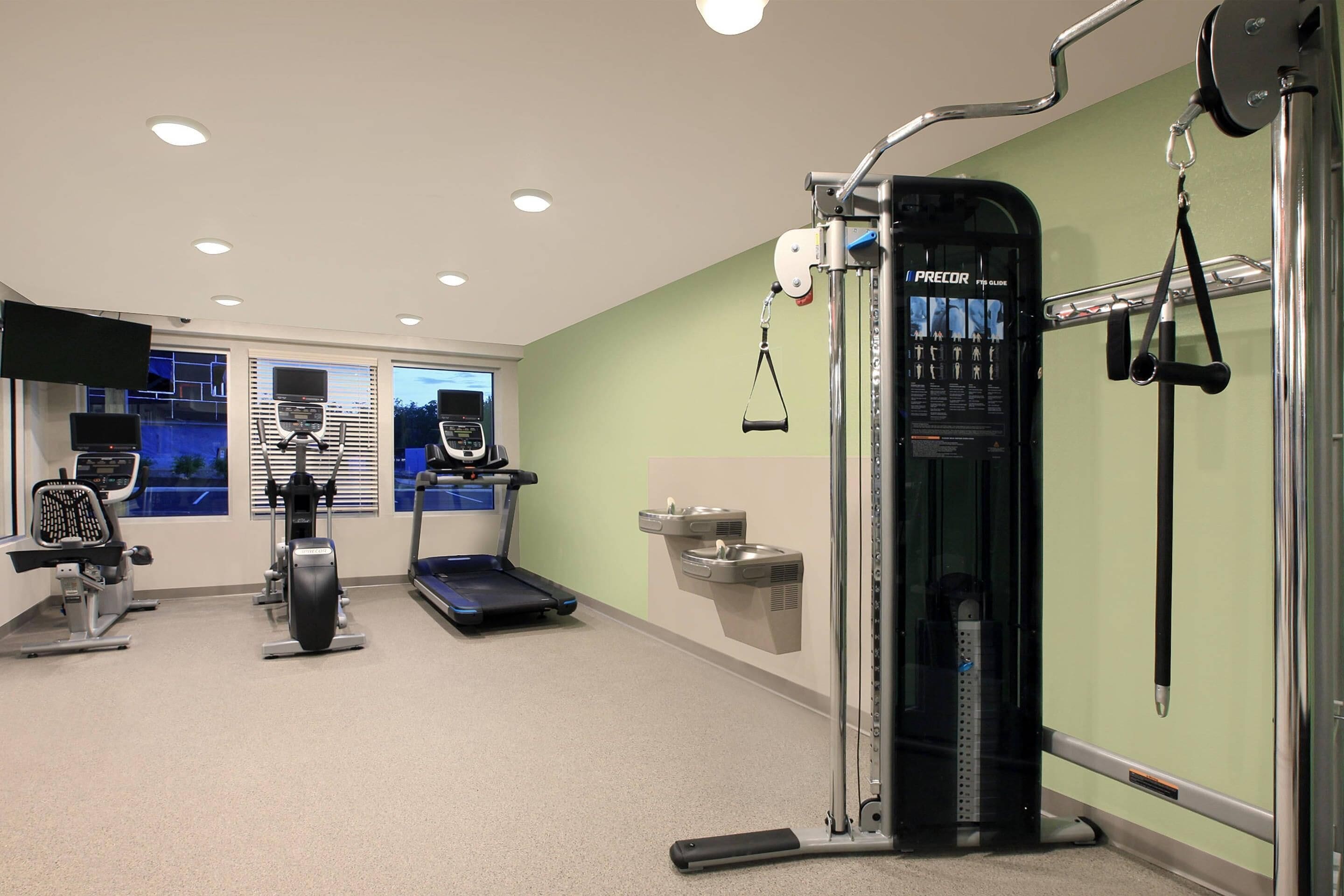 Ginásio com máquinas de cardio, esteira e equipamento de musculação Precor.