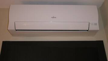 Ar condicionado branco da Fujitsu fixado na parede acima de uma porta escura.