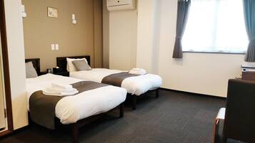 Quarto de hotel com duas camas, uma escrivaninha e uma janela com cortinas.