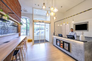 Uma área de bar moderna com piso de madeira, parede de destaque em tijolo e luminárias pendentes.