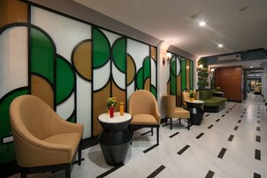 Um lobby moderno com design geométrico na parede, áreas de estar e piso revestido.