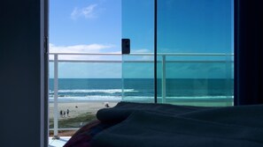 Quarto com uma grande janela com vista para a praia.