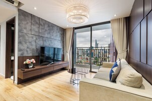 Uma sala de estar moderna com televisão de tela plana, sofá, mesa redonda pequena e varanda com vista para a cidade.