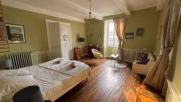 Um quarto com cama, uma cadeira, uma mesa e um radiador.