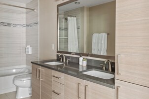 Uma casa de banho moderna com duas pias, sanita e chuveiro.