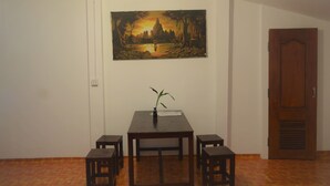 Uma área de refeições com uma mesa e quatro cadeiras, um quadro na parede e uma porta de madeira.