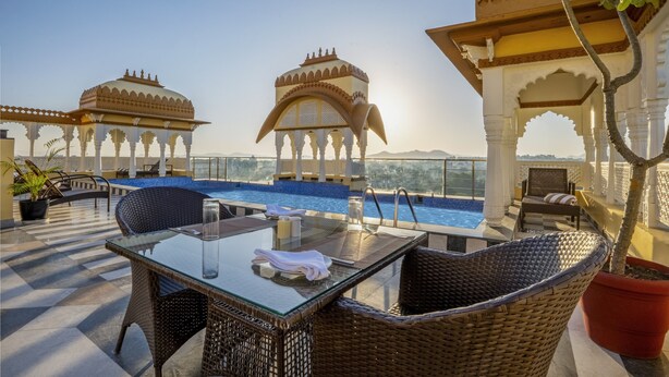 Terraço no topo com piscina, móveis de vime e detalhes arquitetônicos elaborados.