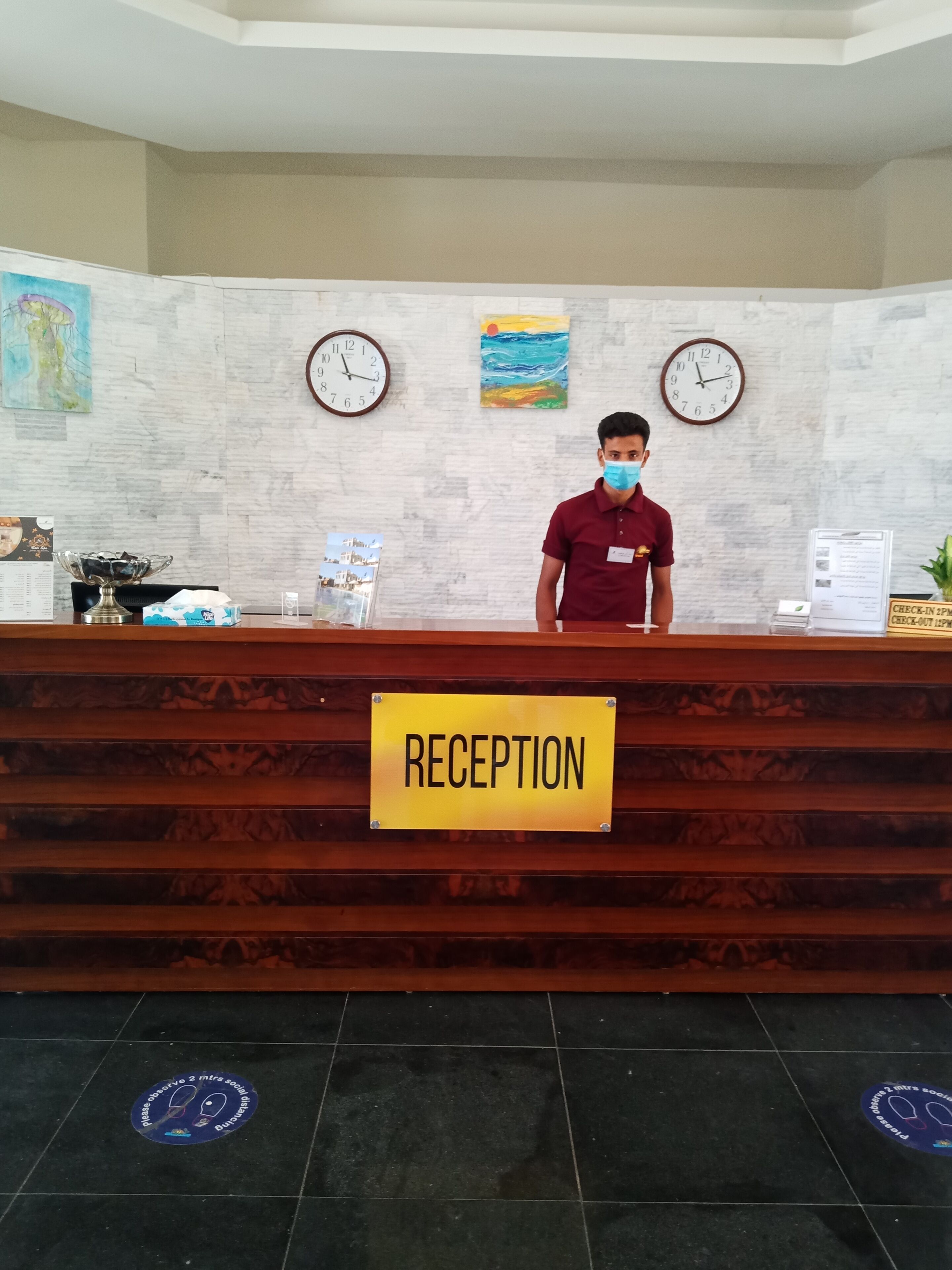 Uma receção com uma placa a indicar "RECEPTION" e dois relógios na parede.