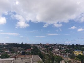 Zona residencial com casas, uma estrada e uma colina ao fundo.