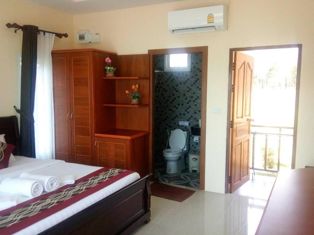 Quarto de hotel com cama, armário, banheiro com vaso sanitário e pia, e ar condicionado.