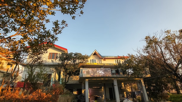 Um edifício de dois andares com telhado vermelho e varanda. O edifício tem uma placa com a inscrição 