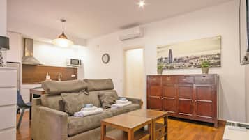 Uma sala de estar moderna com um sofá, uma mesa de centro de madeira, um armário e uma pintura de paisagem urbana na parede.