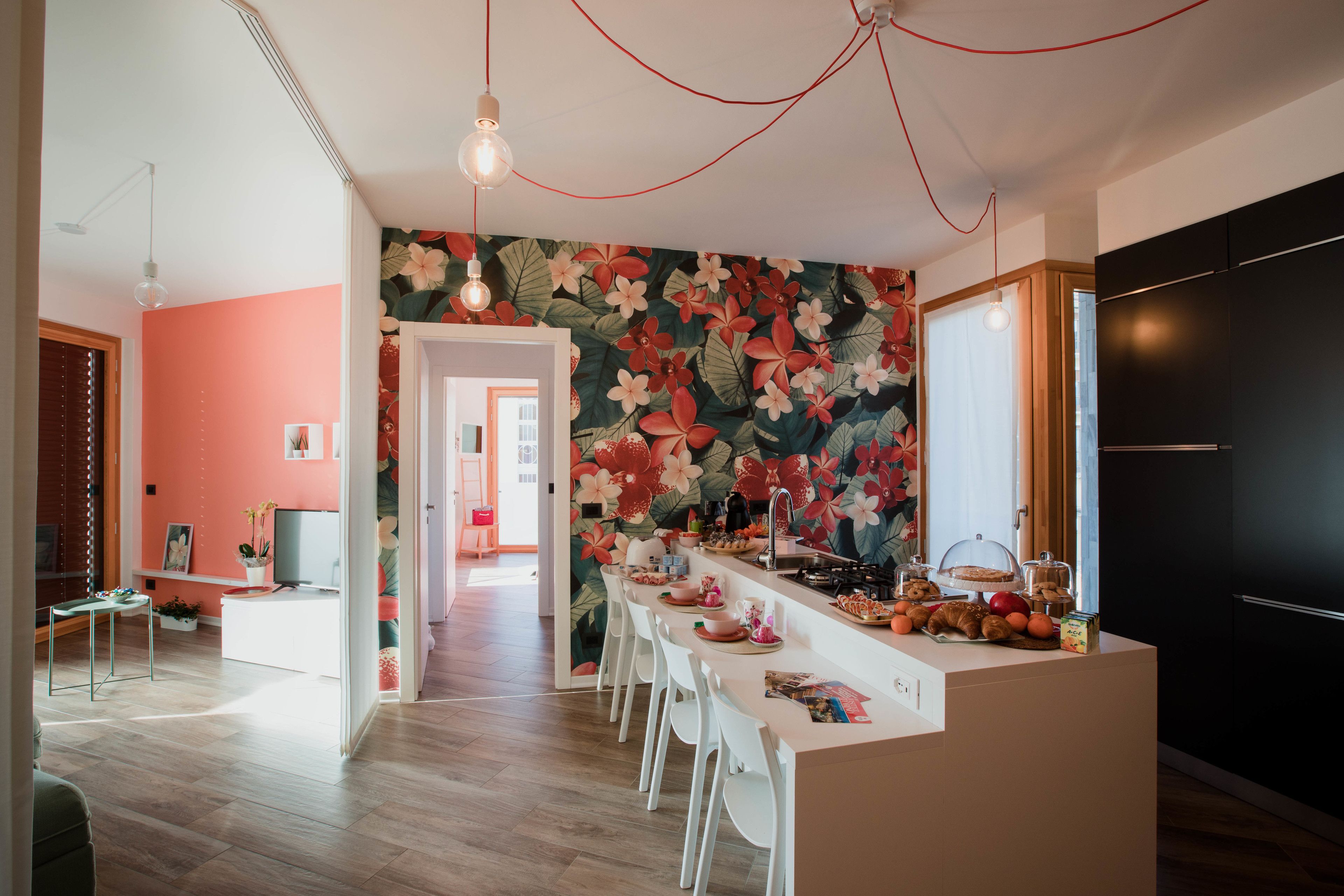 Cozinha moderna com ilha central, cadeiras brancas e um vibrante papel de parede floral.