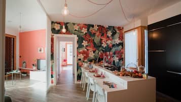 Cozinha moderna com ilha central, cadeiras brancas e um vibrante papel de parede floral.