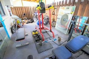 Uma academia em casa com equipamentos de ginástica, incluindo um banco, halteres e um suporte para pesos.