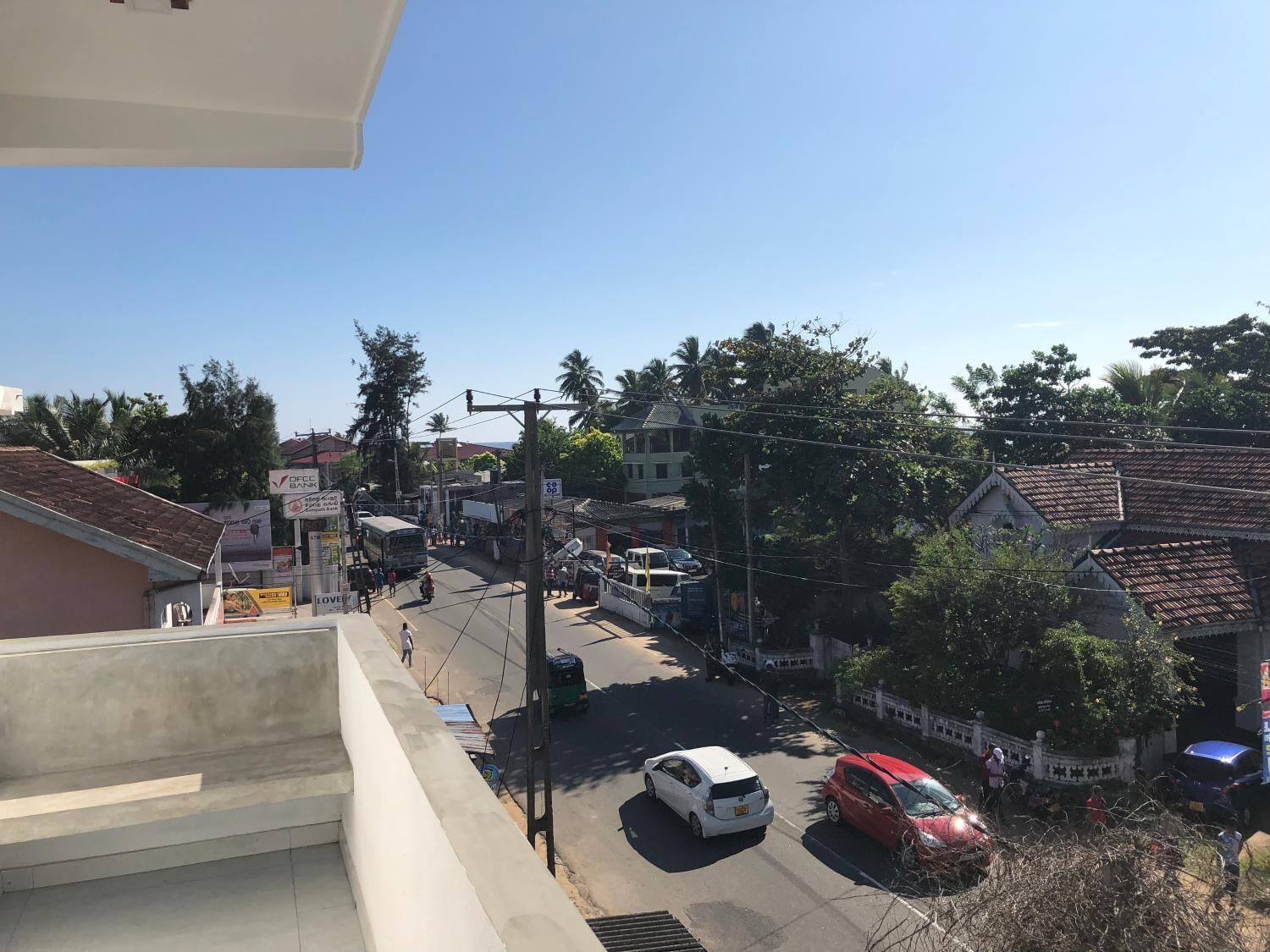 Vista da rua com edifícios, veículos e pedestres.