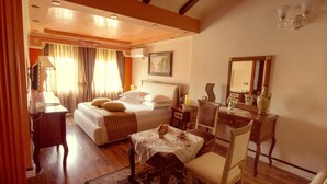 Quarto de hotel com cama, secretária, cadeira, mesa e espelho.