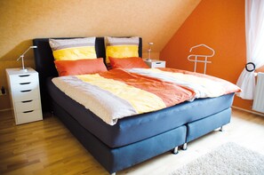 Quarto com cama, mesas de cabeceira, guarda-roupa e radiador.