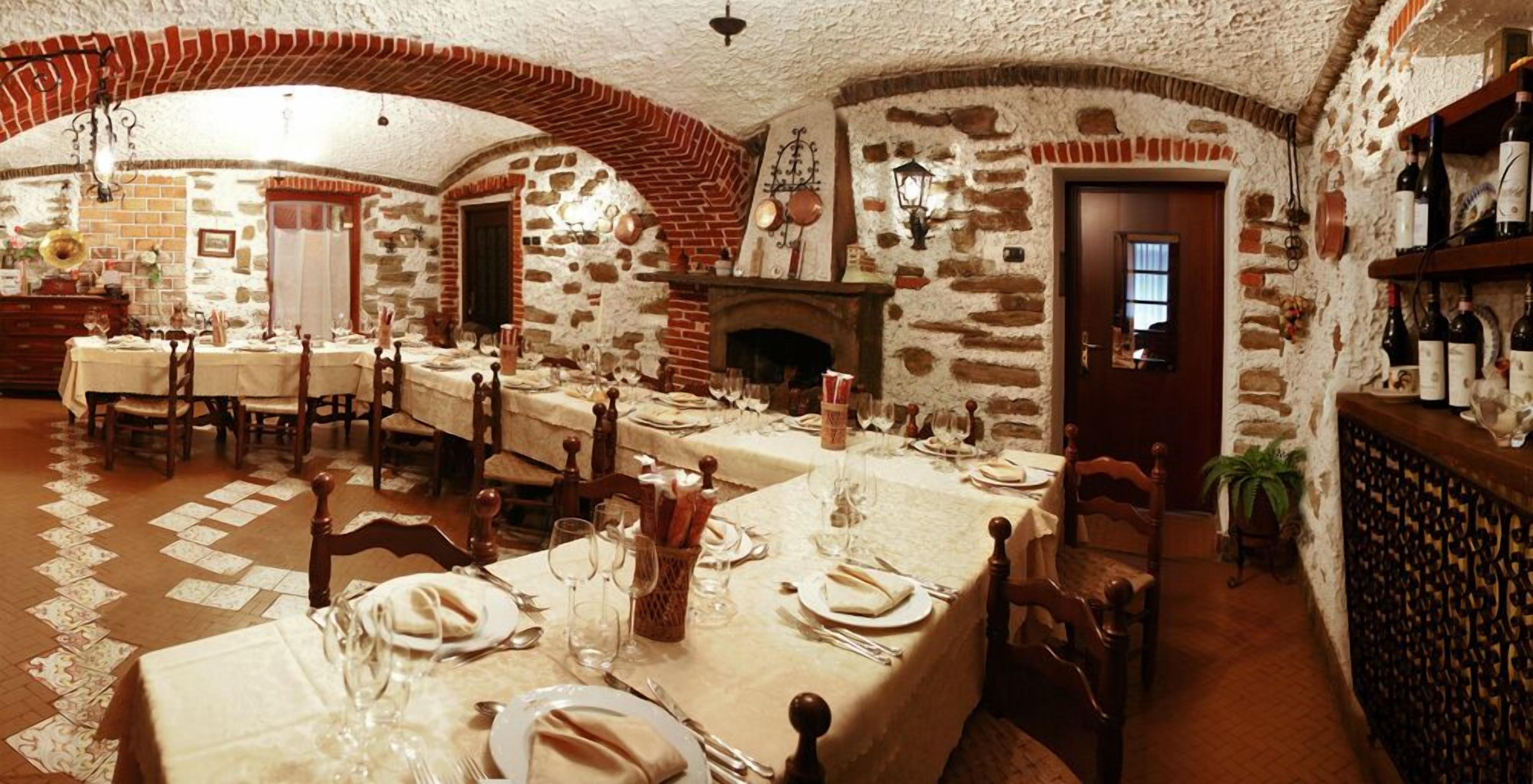 Uma sala de jantar com paredes de pedra, mesas de madeira e lareira.