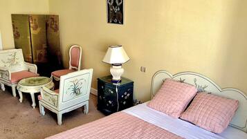 Quarto com cama grande, escrivaninha, cadeira e cômoda.