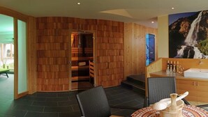 Uma sala de spa com paredes de madeira, uma mesa de massagem, uma pia e uma grande janela com vista para uma cascata.