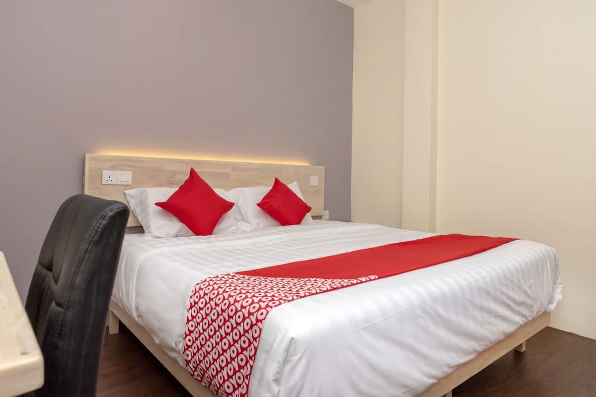 Cama bem arrumada com roupa de cama branca e vermelha, cabeceira de madeira e manta vermelha.