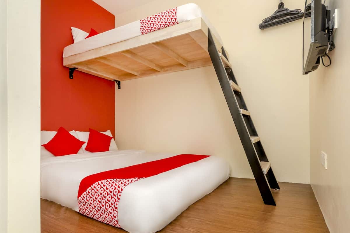 Uma cama de beliche com escada, roupa de cama vermelha e branca, e uma parede vermelha.