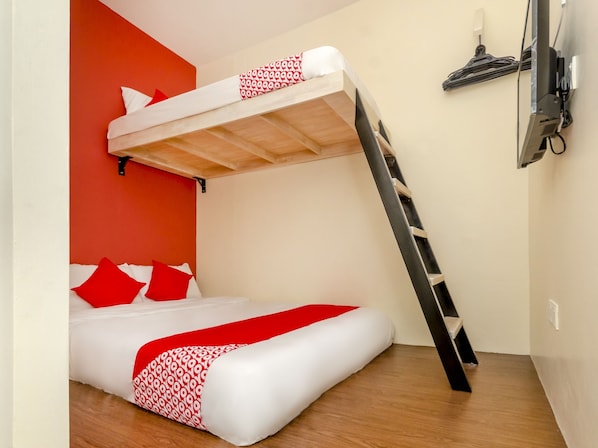 Uma cama de beliche com escada, roupa de cama vermelha e branca, e uma parede vermelha.