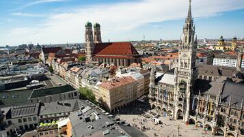Uma praça histórica na cidade, com arquitetura gótica marcante, incluindo uma torre alta e um edifício com duas cúpulas.