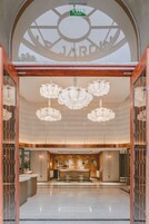 Um lobby com recepção, teto decorativo imponente e um mural na parede.