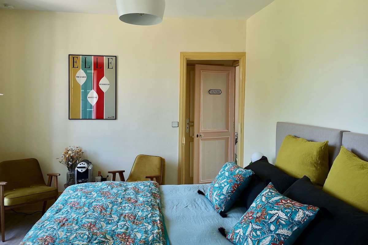 Quarto com cama, cadeira, escrivaninha, um vaso de flores e uma porta com a inscrição 'Valentine'.