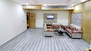 Uma sala de estar moderna com um sofá seccional, uma mesa de centro e uma televisão de tela plana fixada em uma parede de madeira.