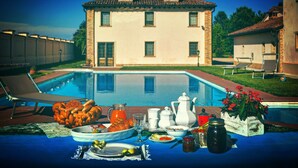 Uma mesa de jantar com itens de café da manhã e vista para uma piscina e um edifício ao fundo.