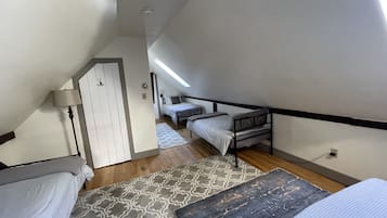 Quarto de dormitório com duas camas, uma escrivaninha, uma luminária e um tapete estampado.