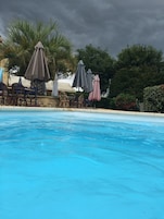 Uma piscina com espreguiçadeiras e guarda-sóis.