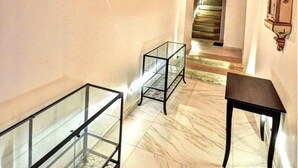 Um corredor com uma vitrine de vidro, uma mesa de madeira e uma escada que leva a outro espaço.