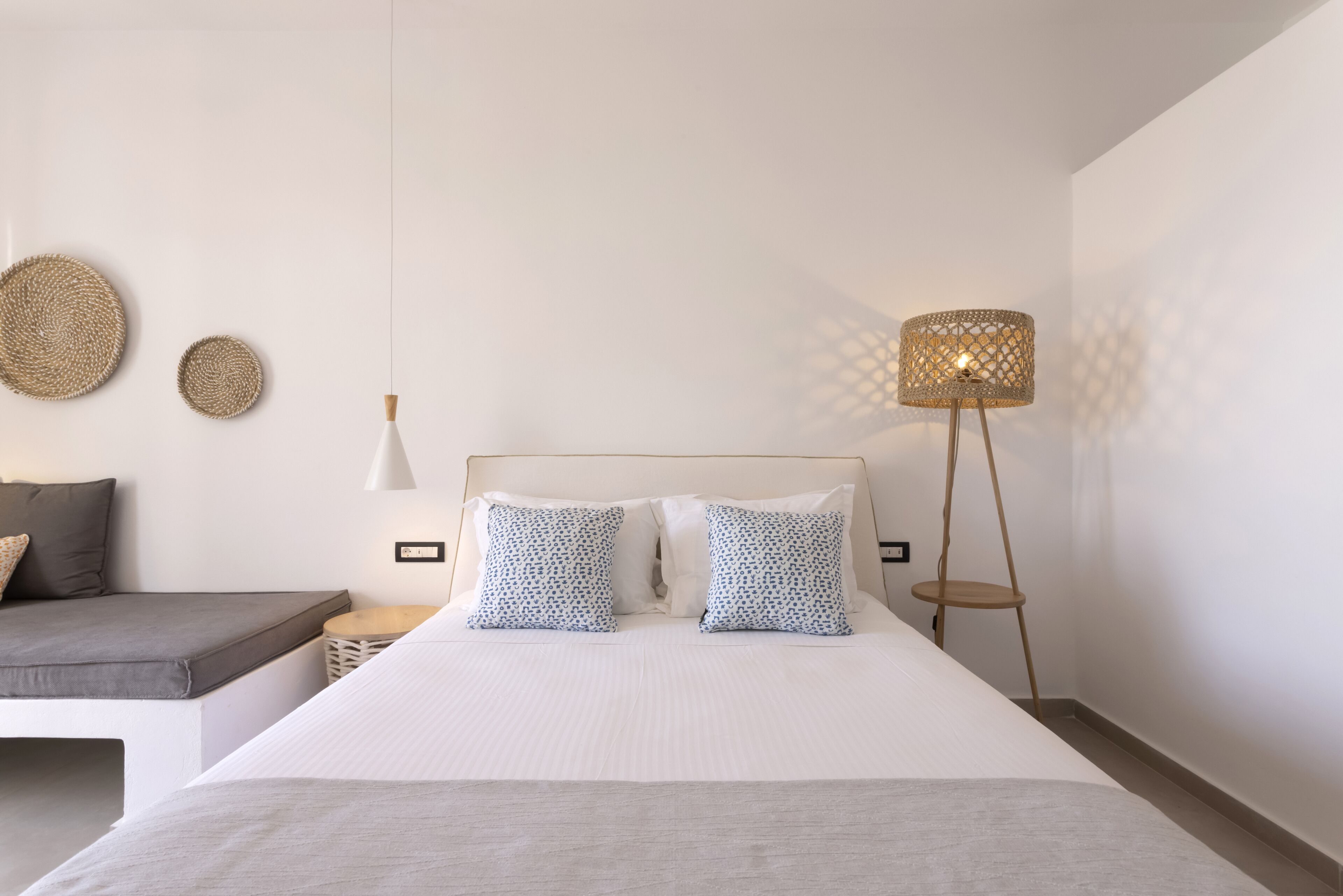 Um quarto moderno com uma cama grande, uma mesa de cabeceira, um abajur e uma prateleira na parede.