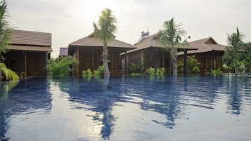 Um resort com piscina, cercado por edifícios de madeira e palmeiras.