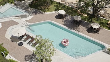 Uma grande piscina retangular com um flutuador de flamingo rosa, cercada por espreguiçadeiras e guarda-sóis.