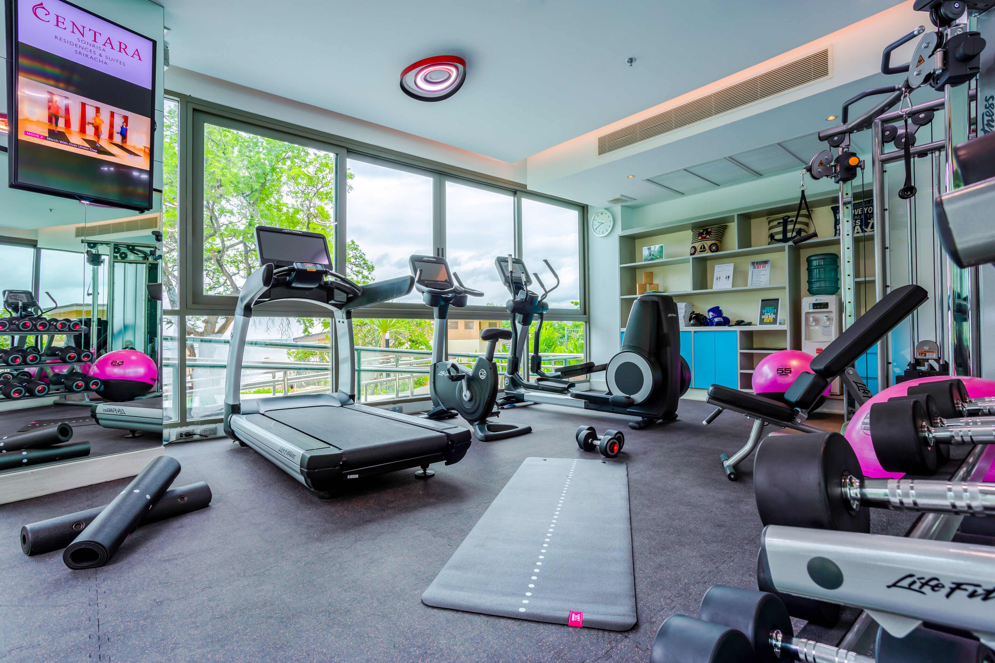 Academia moderna com máquinas de cardio, pesos livres e um espelho grande.