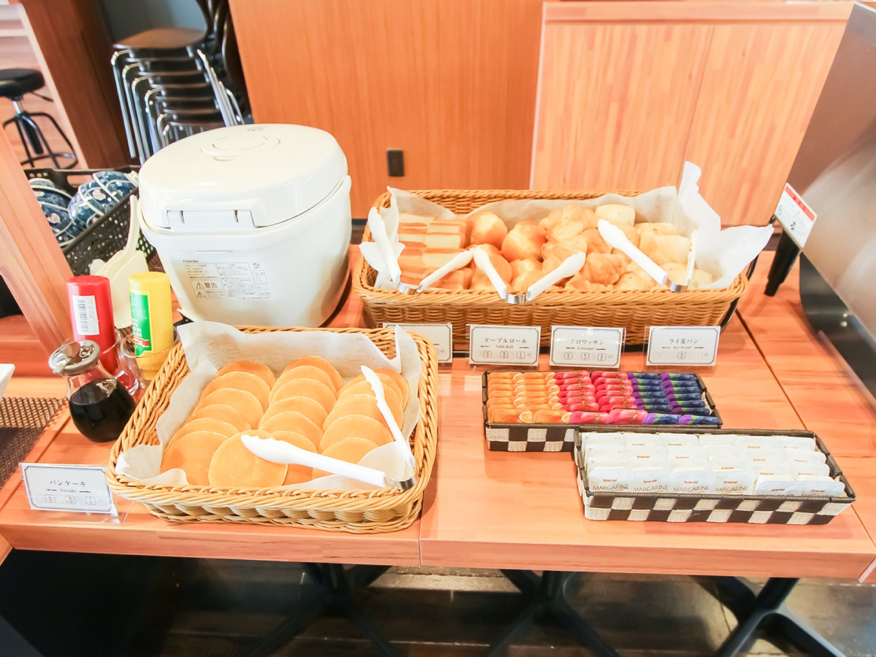 Buffet com diversos alimentos, incluindo pão, doces e acompanhamentos.