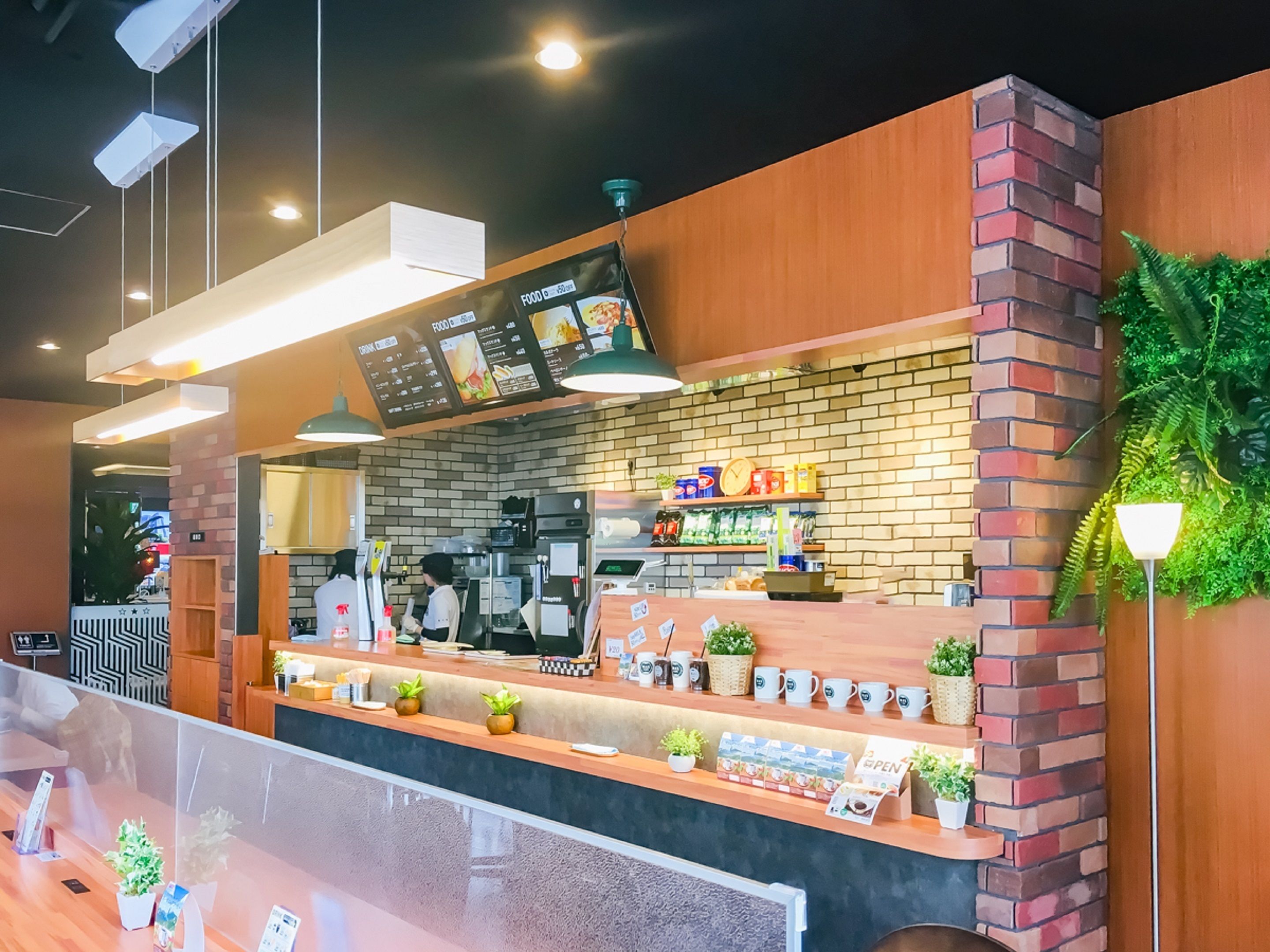 Interior de uma cafeteria com balcão, cardápio e área de estar.