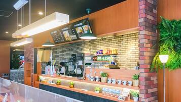 Interior de uma cafeteria com balcão, cardápio e área de estar.