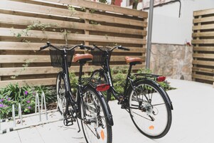 Duas bicicletas encostadas a uma cerca de madeira com um muro de pedra ao fundo.