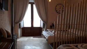 Um quarto com cama, cabeceira de madeira, relógio na parede e janela com cortinas.