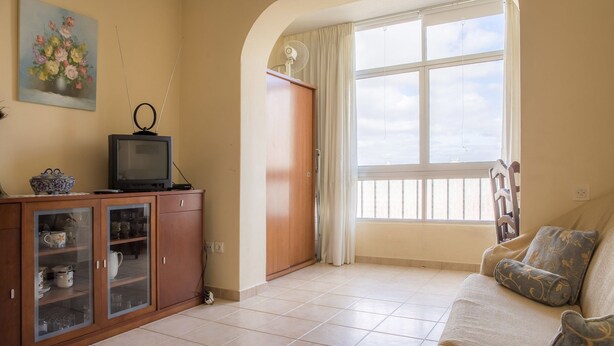 Uma sala de estar com televisão, um armário de madeira e um sofá.