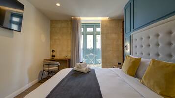 Quarto de hotel com uma cama grande, uma mesa e vista para o exterior.